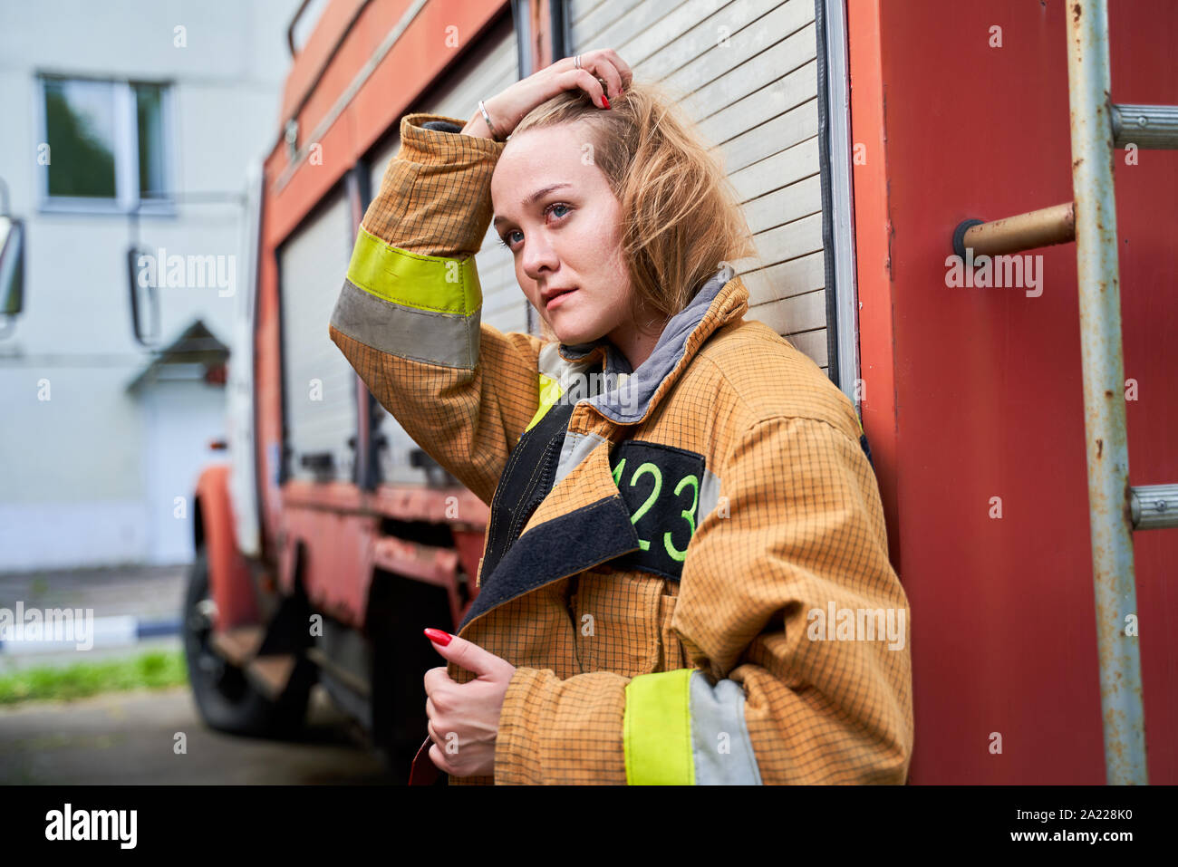 Image of firefighter woman next to fire engines on street on summer day ...