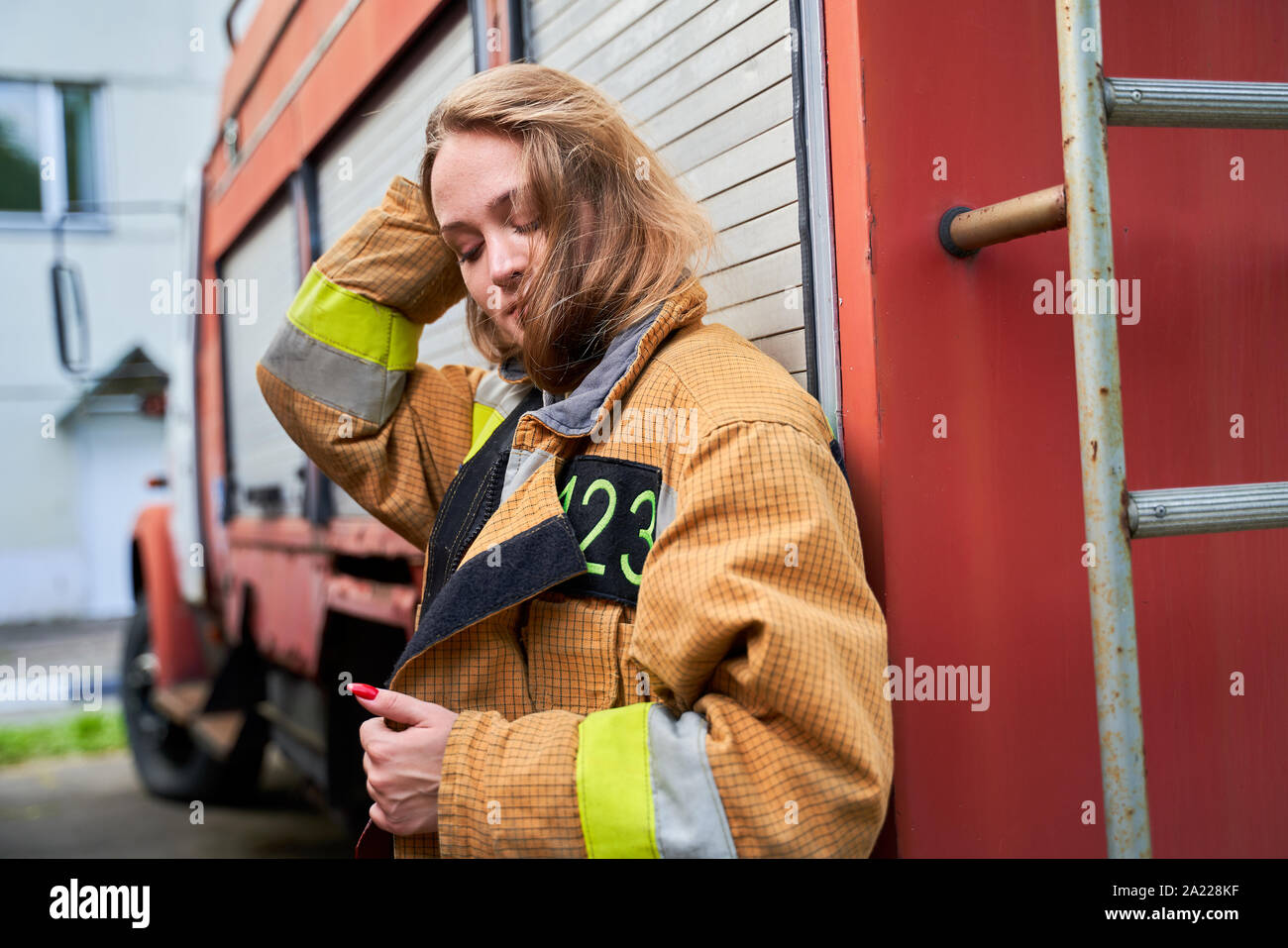Image of firefighter girl next to fire engines on street on summer day ...