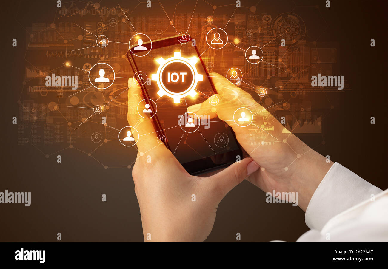 Female hand holding smartphone with IOT abbreviation, modern technology ...