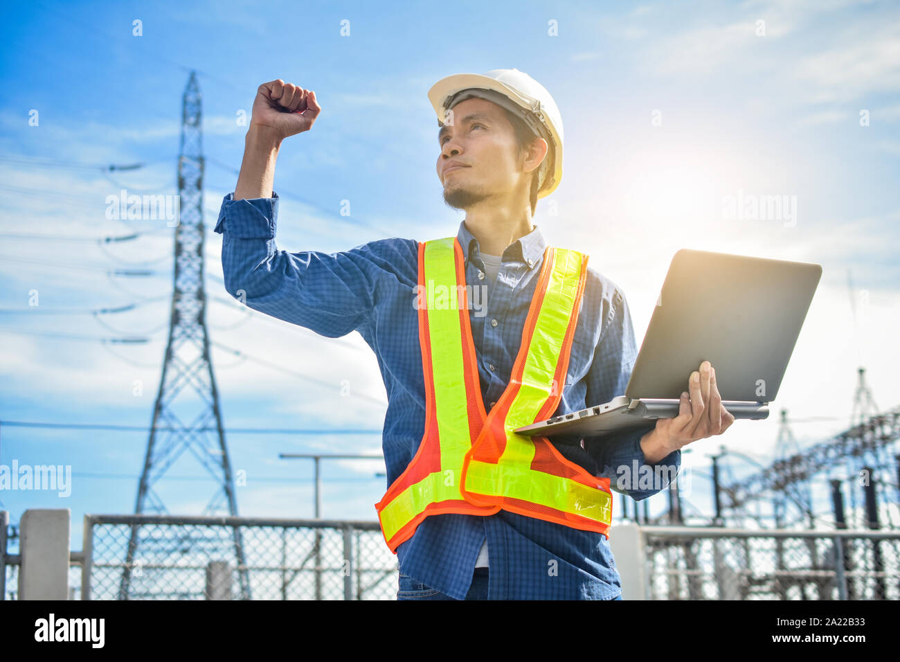 Engineer holding Computer notebook or laptop and a power plant with the ...