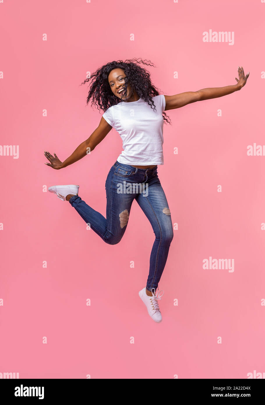 Stunning young african girl jumping over pink studio background Stock ...