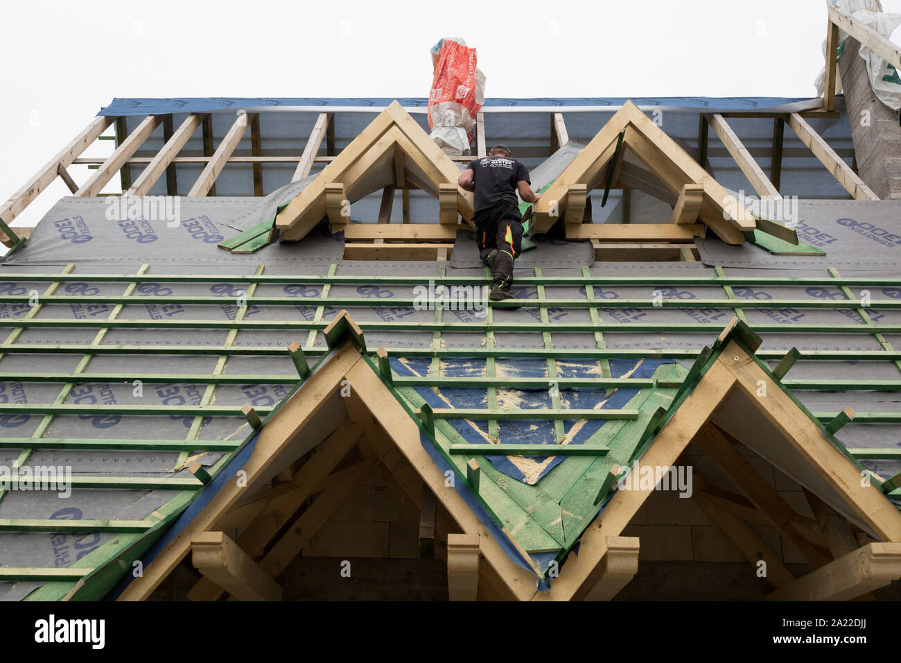 A workman balances on the tile supports of a new Polish house's roof ...