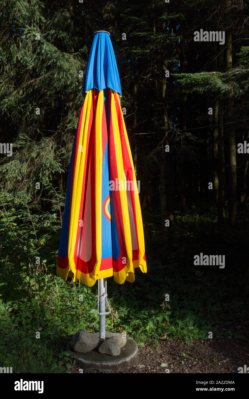 A landscape of a folded parasol standing in woods near the entrance of ...