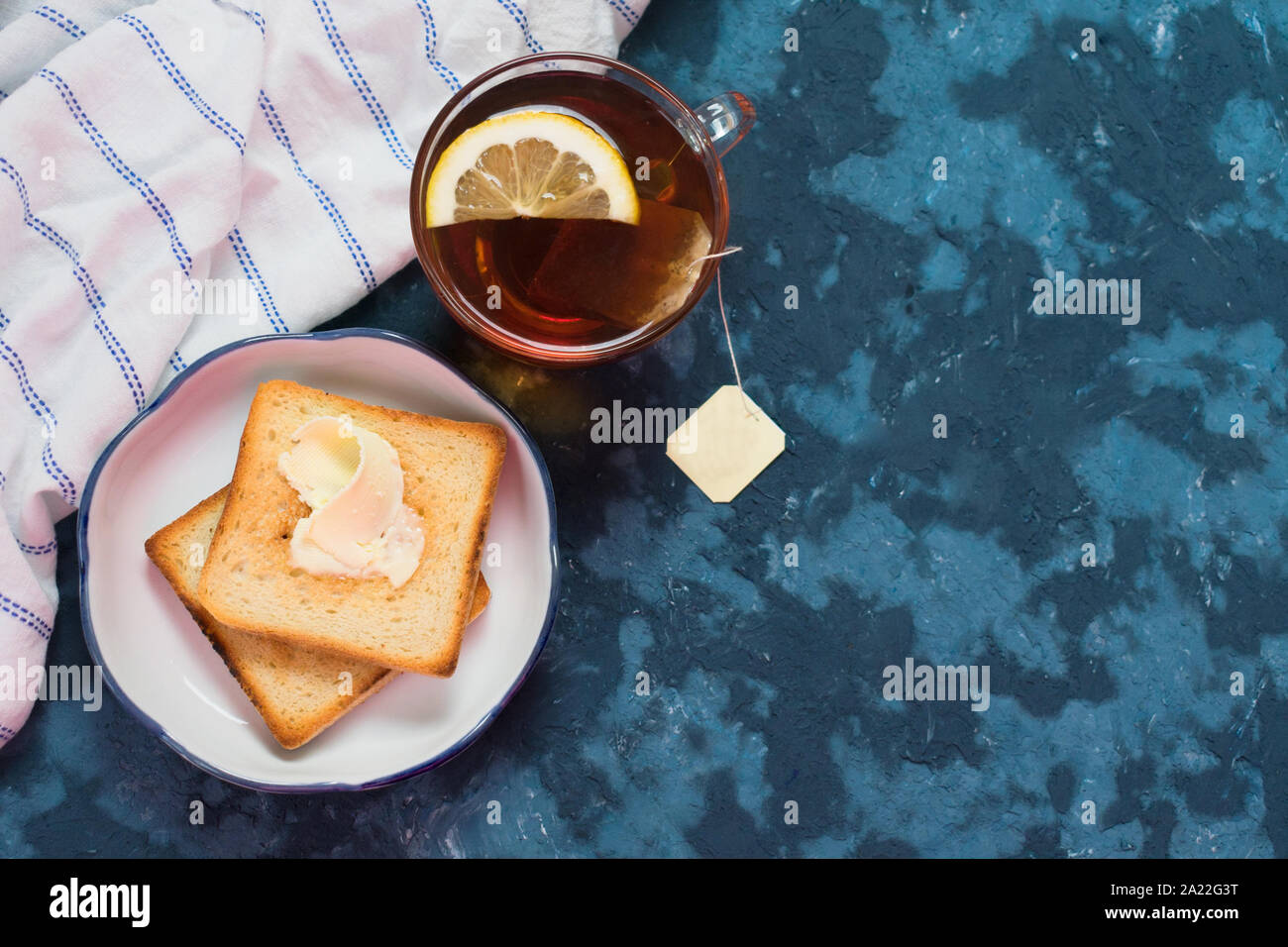 Toaster with butter and tea with lemons on a blue background. Light ...