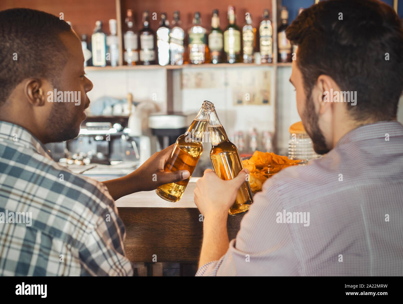 Two cheerful mixed race mates having fun together in pub, clinking beer ...