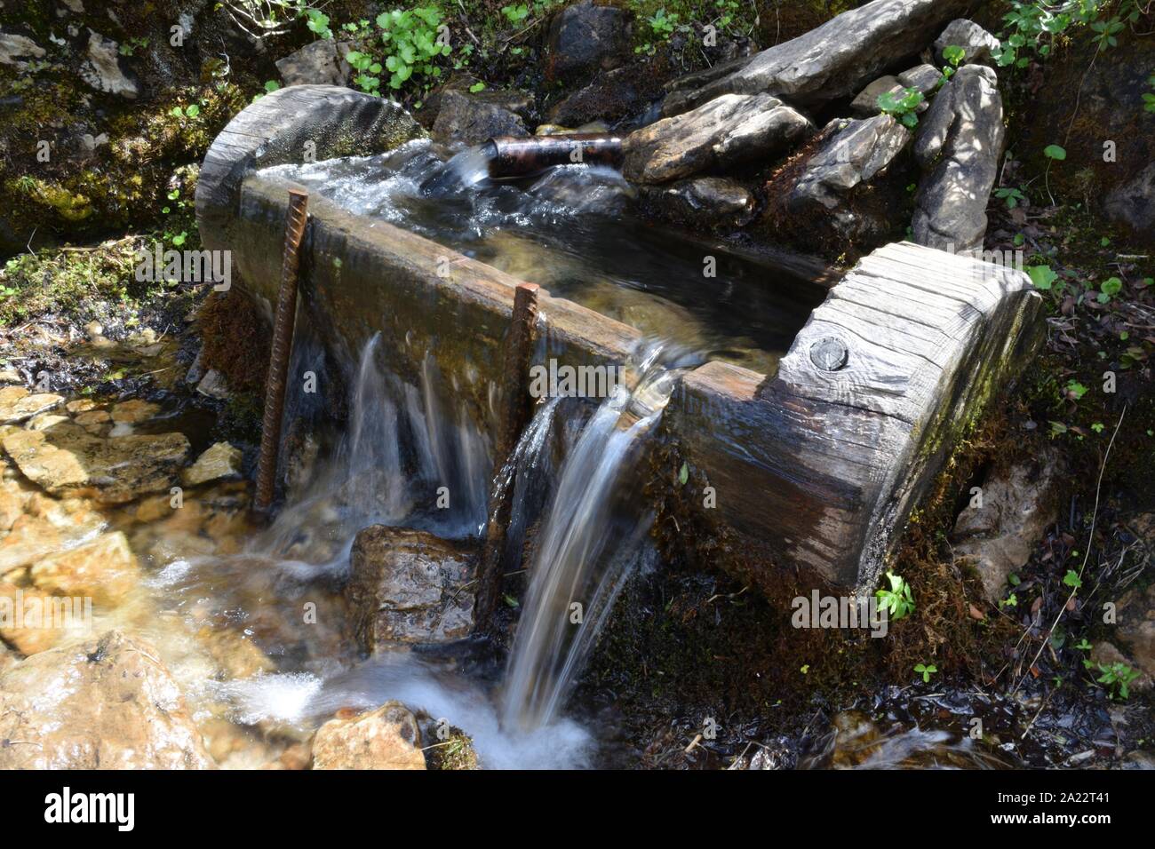 typical alpine wooden water fountain overflowing with fresh water at ...