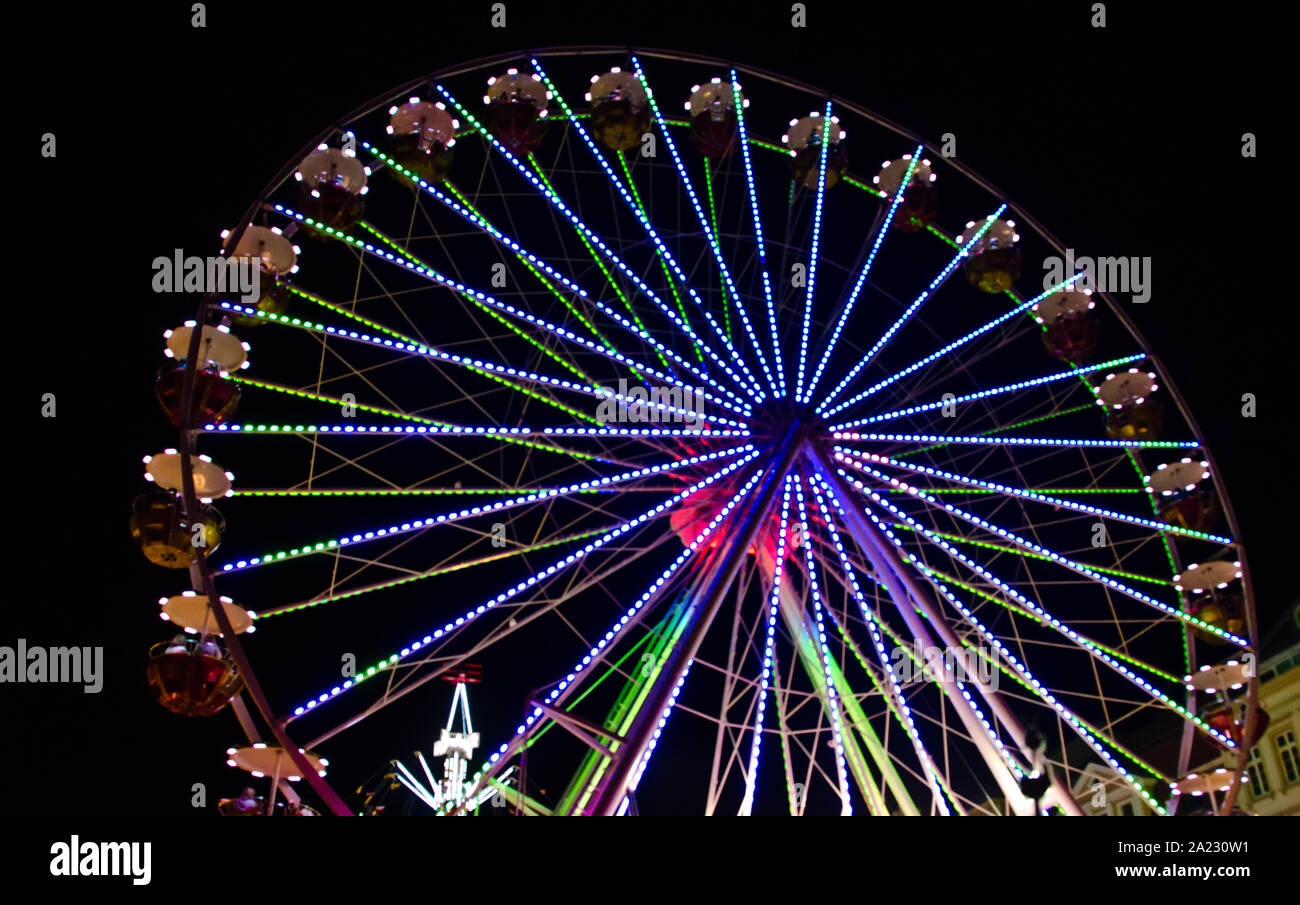 A colourful ferris wheel carousel at a fun fair at night Stock Photo ...