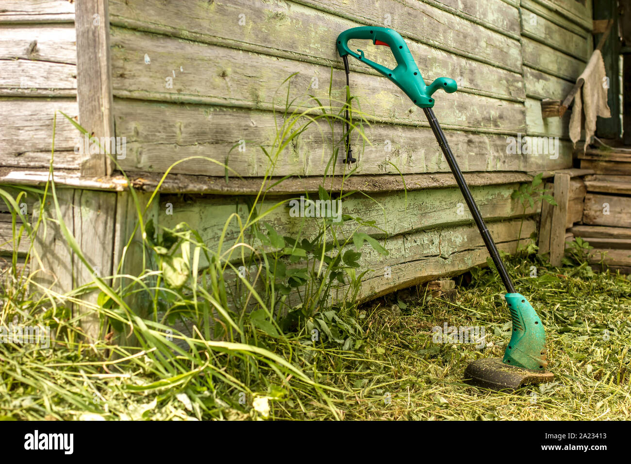 electric grass trimmer stands in the garden near the house, simply ...