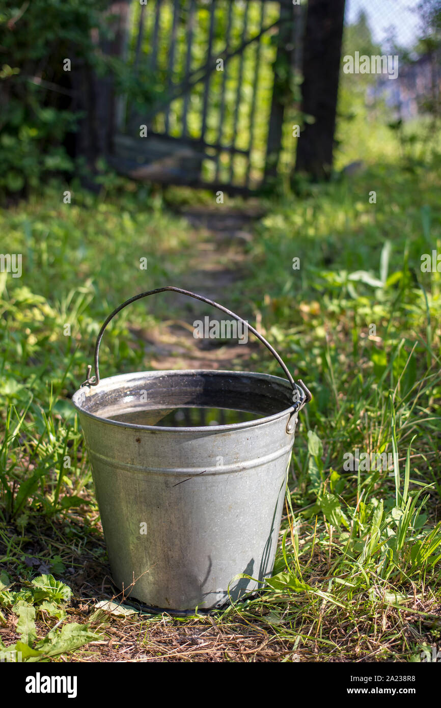 metallic bucket with pure drinking water stands on the footpath in the ...