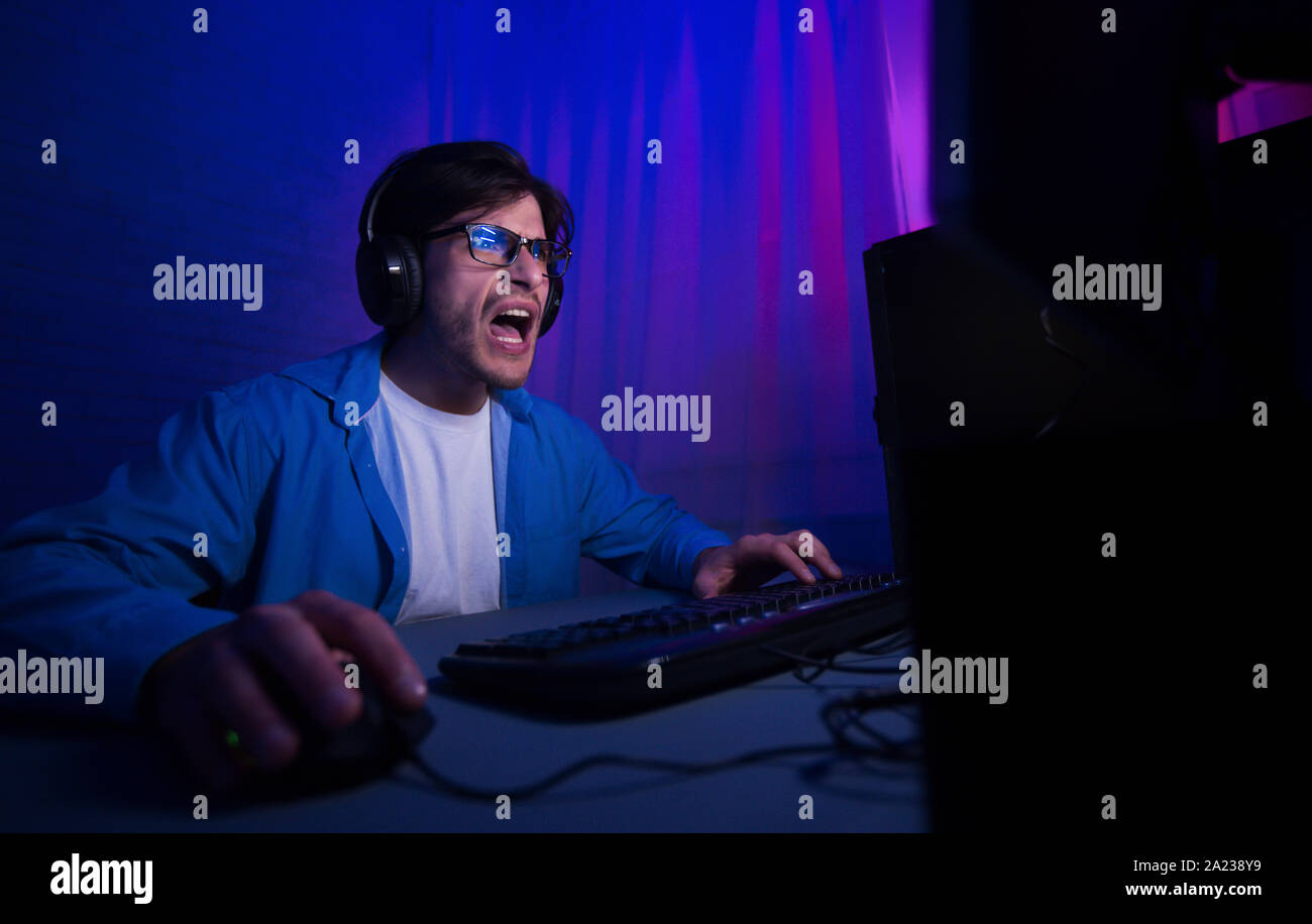 Emotional gamer playing video game online and shouting, wearing headset ...