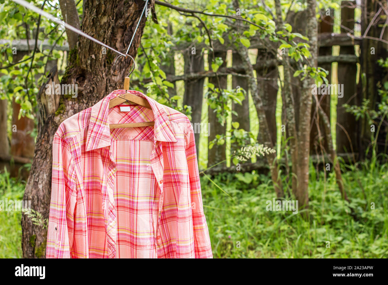 Shirt hangs a on hanger on the rope in a village on the background of ...