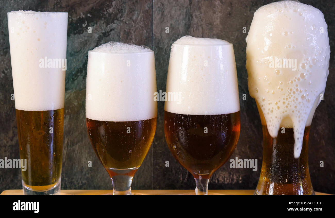 Pouring beer into traditional beer glasses on black slate bar table ...