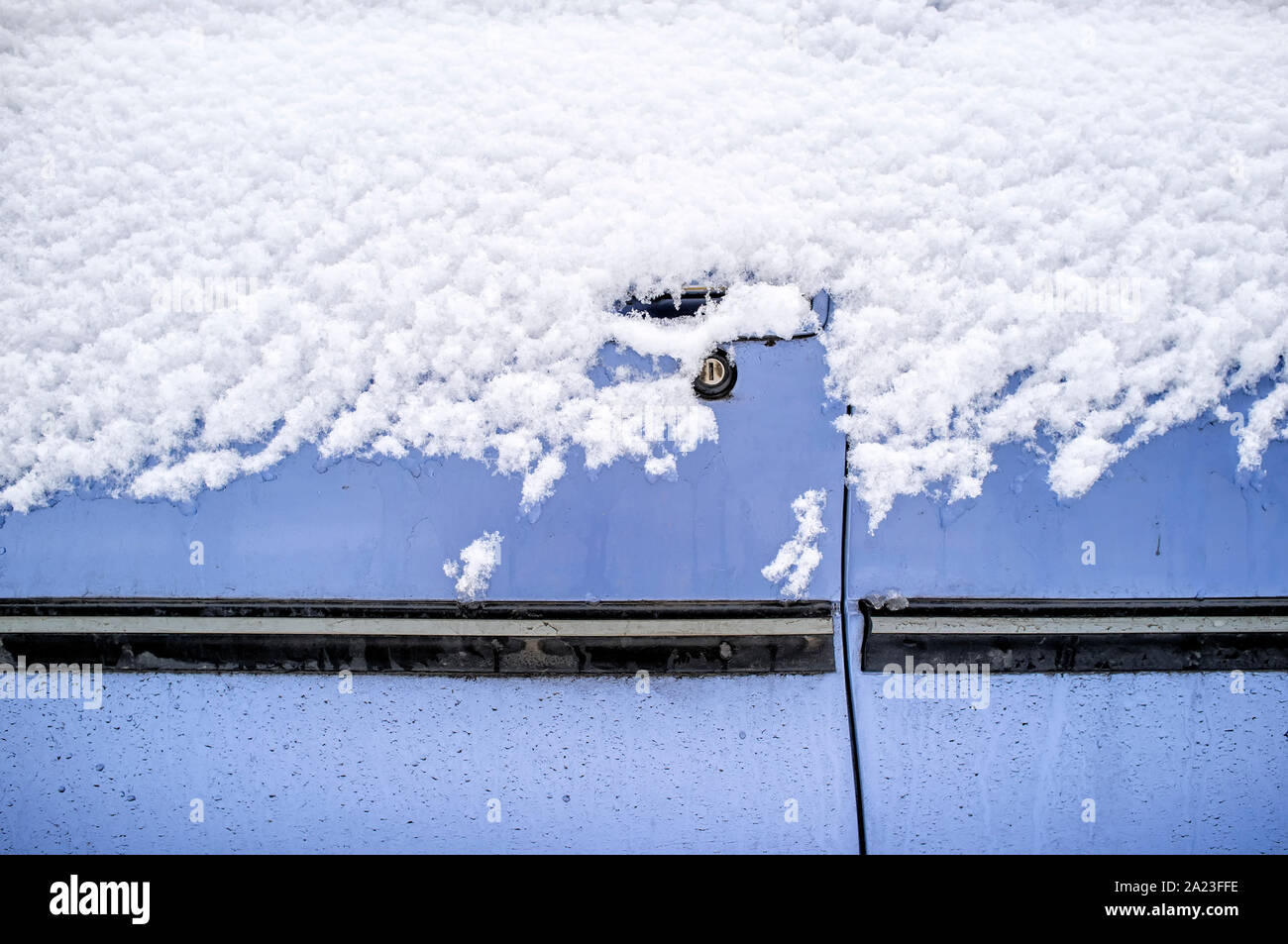 keyhole and handle of blue car covered with snow in winter in frost ...