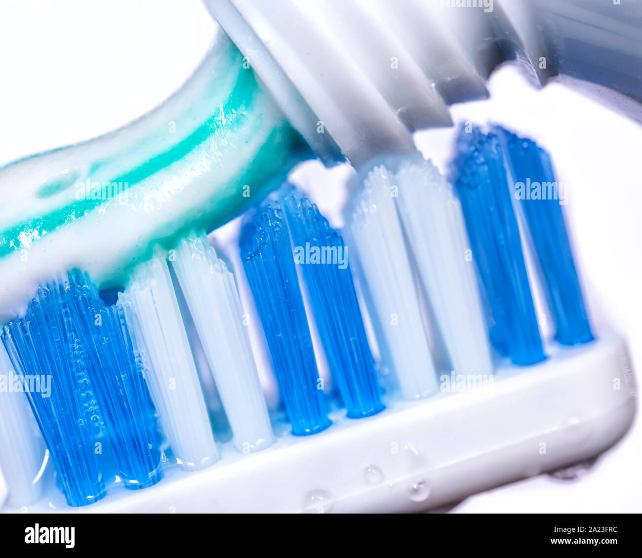 Macro blue toothbrush coated striped toothpaste on a white background ...