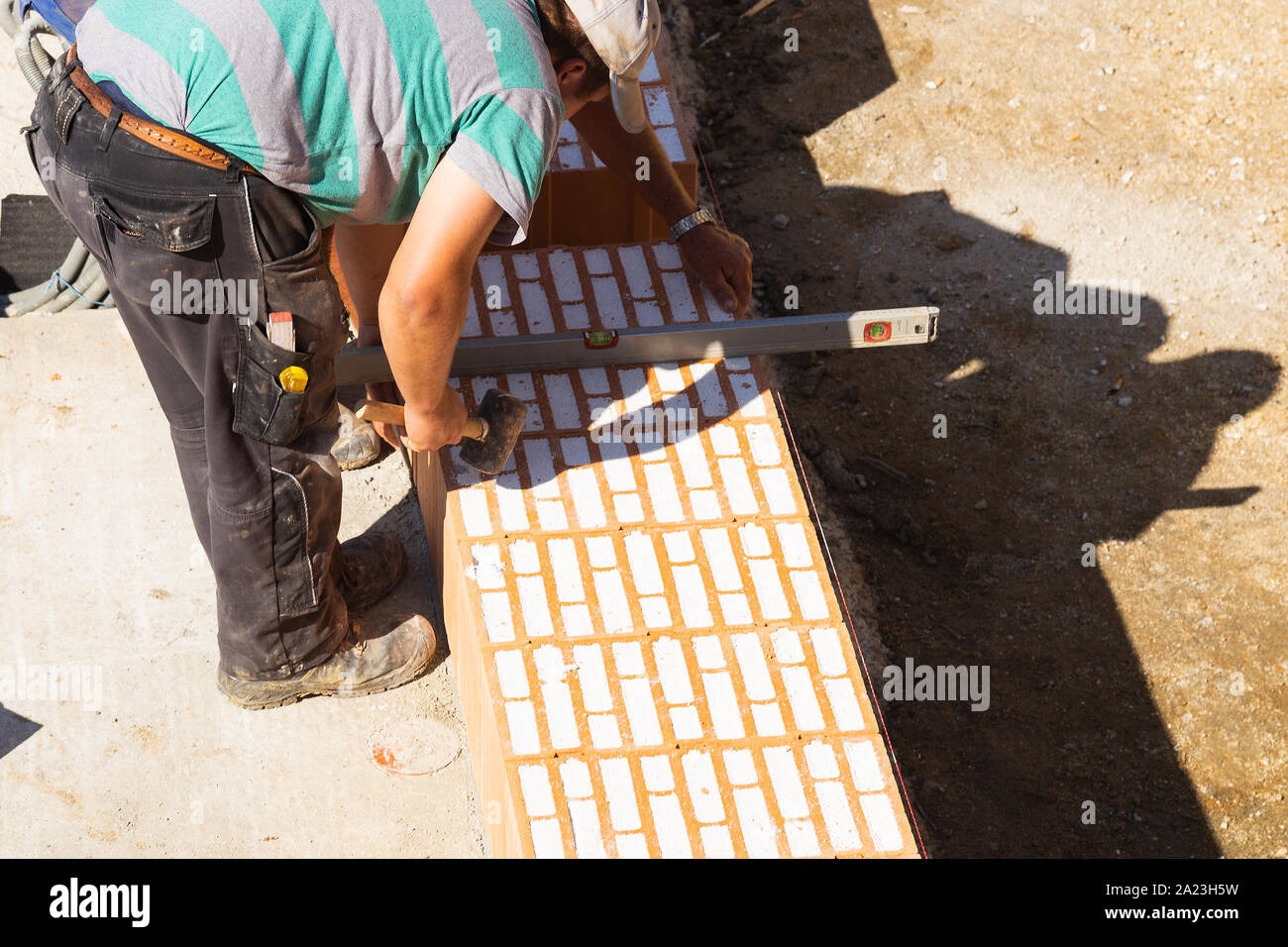 Two bricklayers are working on a construction site with a spirit level ...
