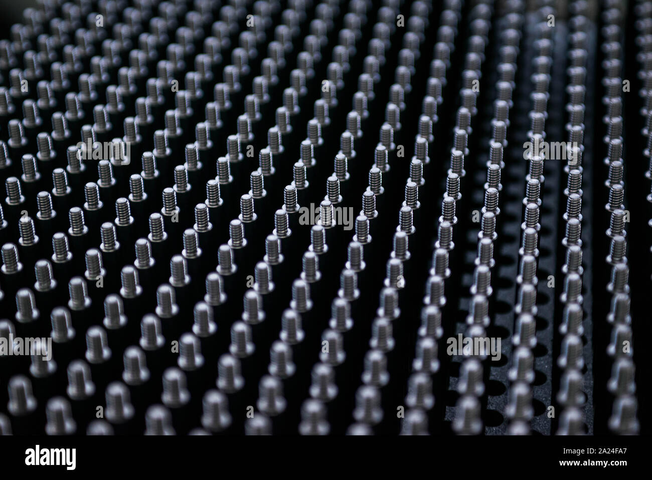 Close up shot of black screw thread bolts rowed up to a pattern ...