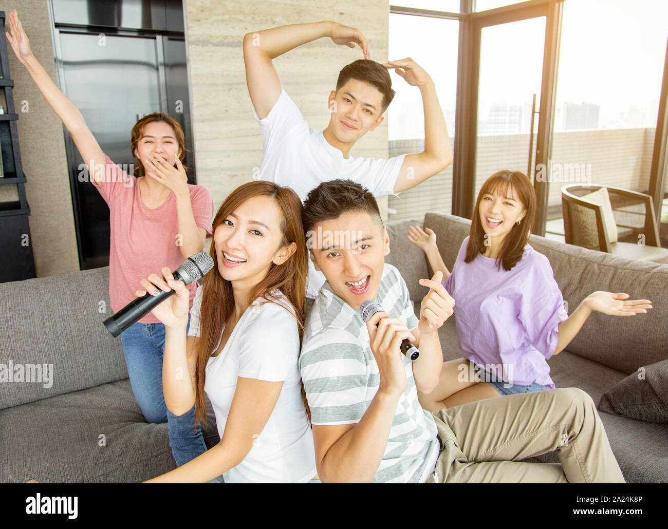 Group of friends playing karaoke at home Stock Photo - Alamy