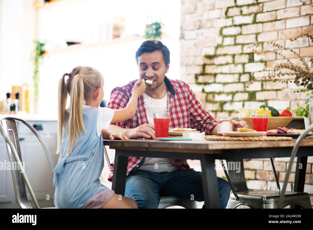 Lovely daughter feeding daddy while having breakfast Stock Photo - Alamy