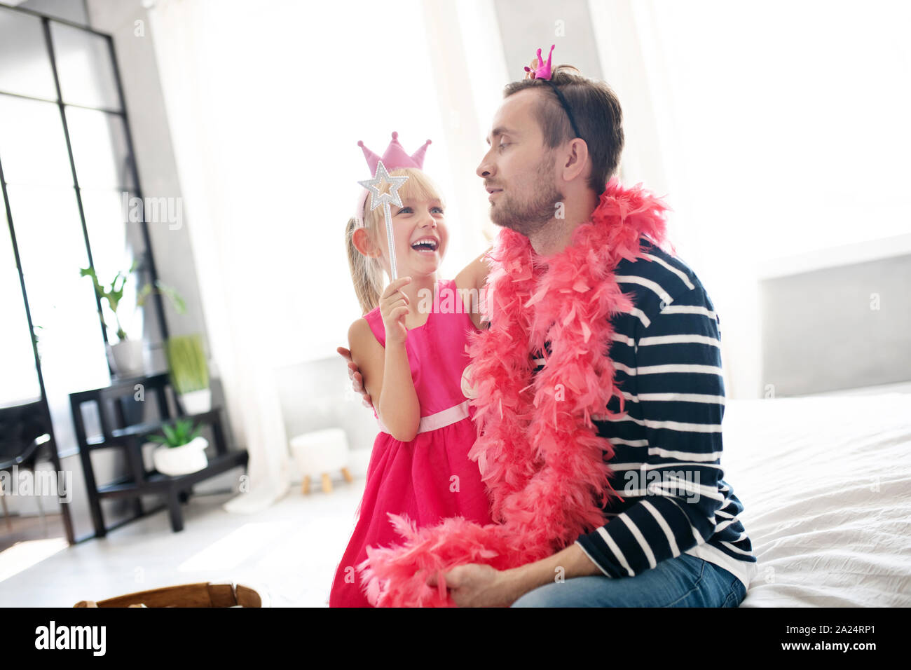 Daughter holding magic stick while playing with dad Stock Photo - Alamy