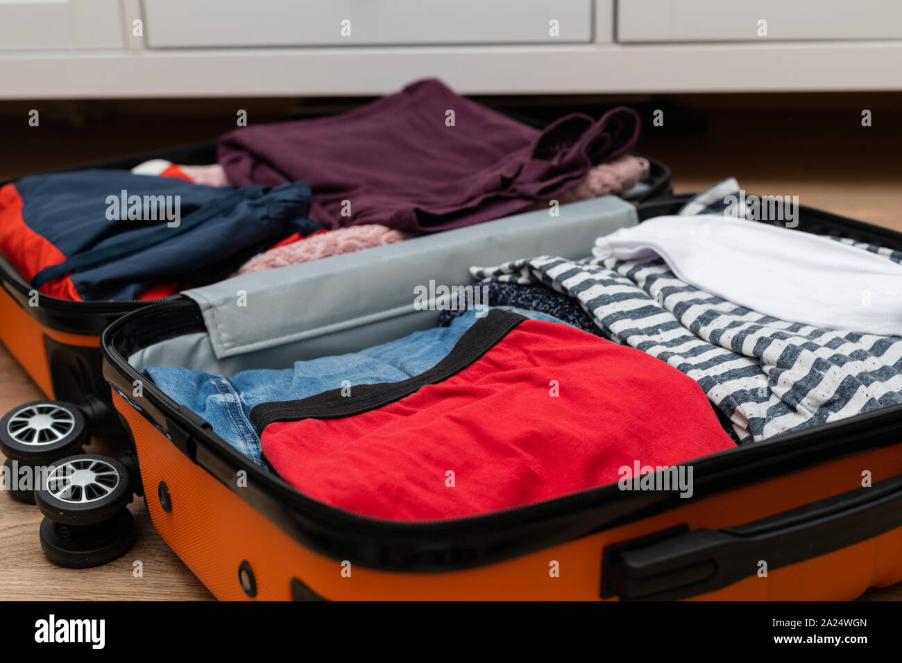 Traveler suitcase full of clothes at cozy modern apartment Stock Photo ...