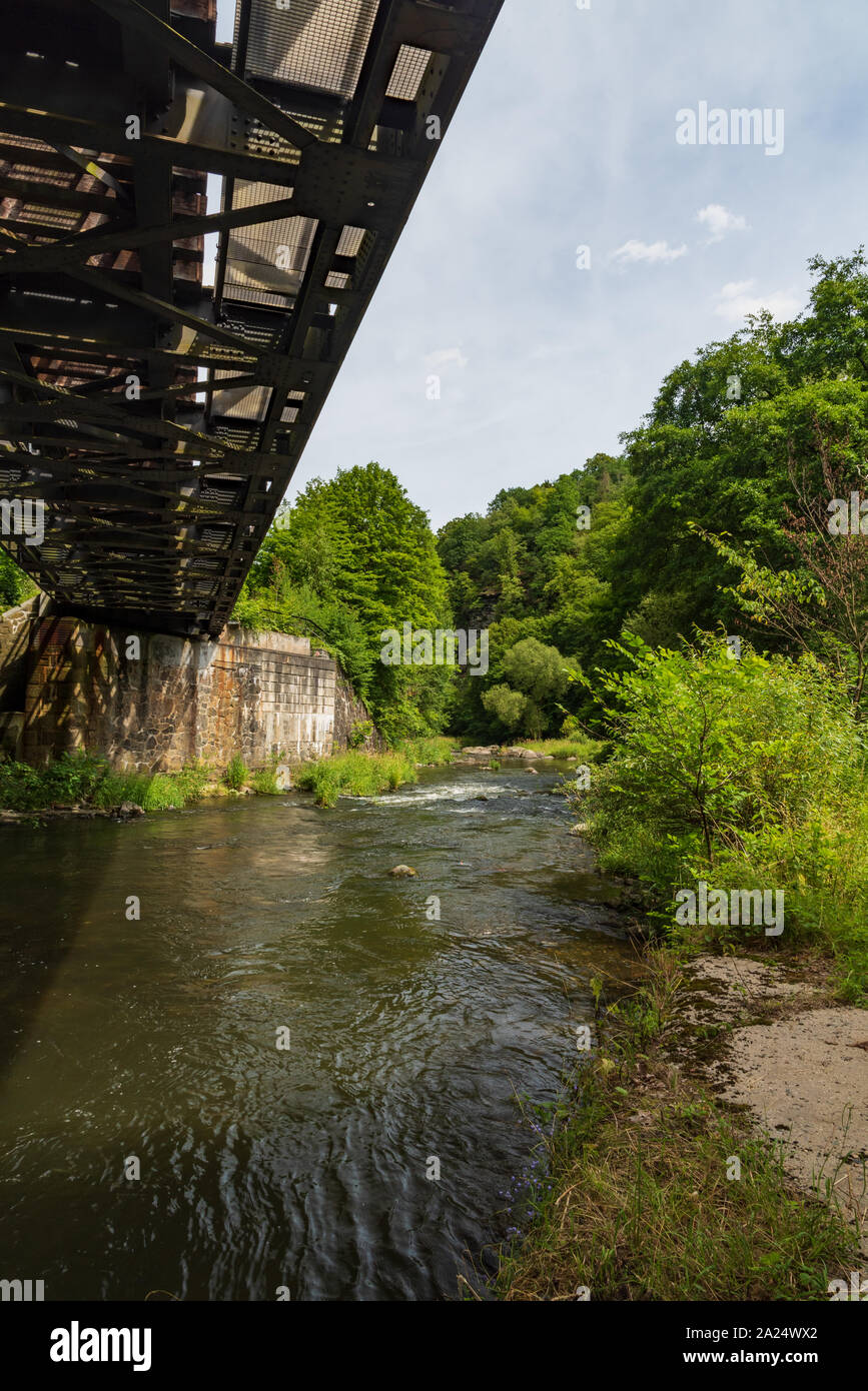 Weisse Elster river with railway bridge above and trees around between ...