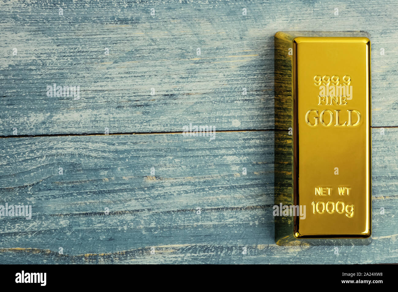Ingot of pure gold metal bullion on a background of blue wooden boards ...