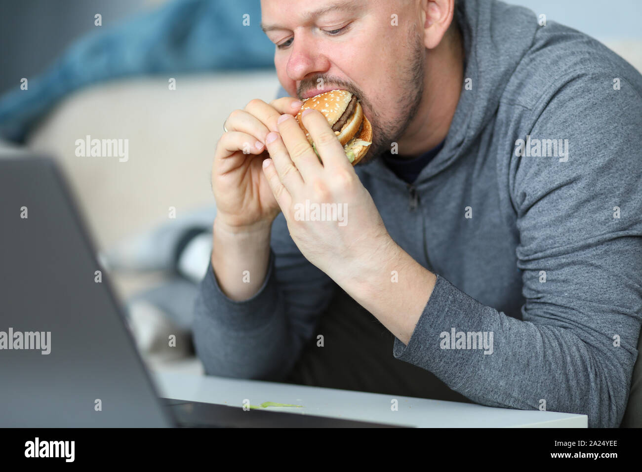Man sit on sofa and eating burger against flat Stock Photo - Alamy