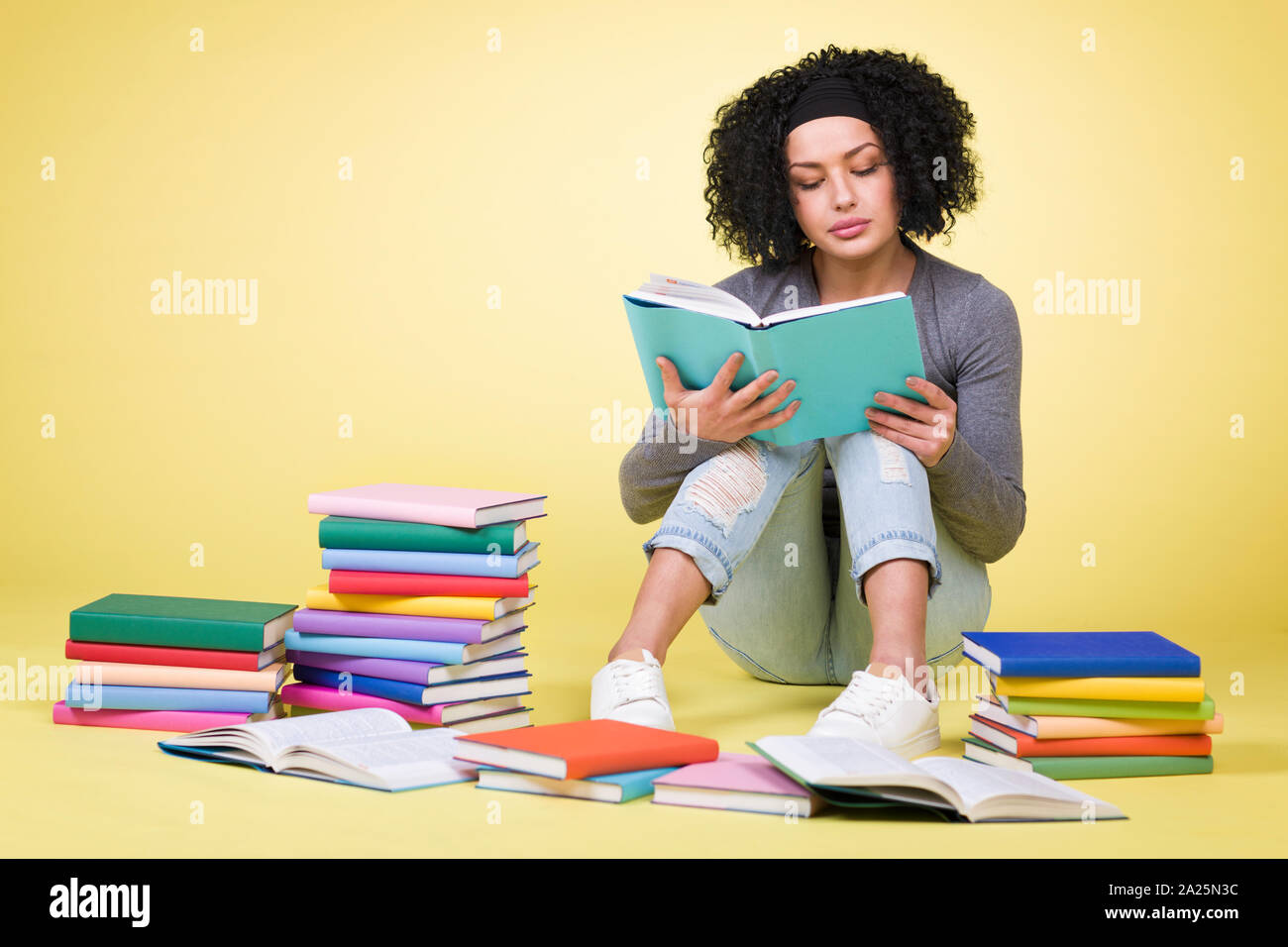 Focused student girl learning surrounded by colorful books Stock Photo ...