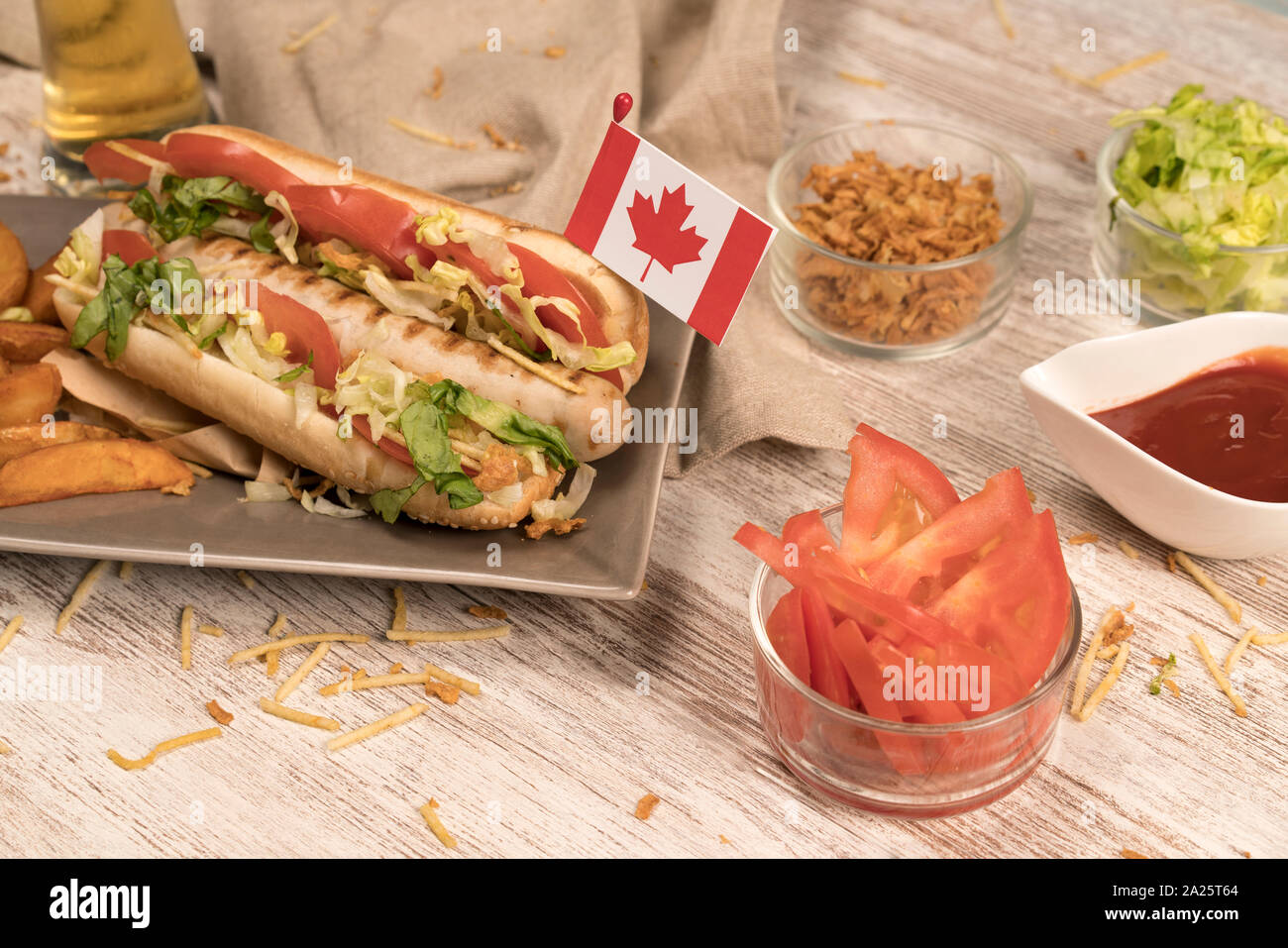 Homemade hot dog on white wooden board with various condiments top view ...