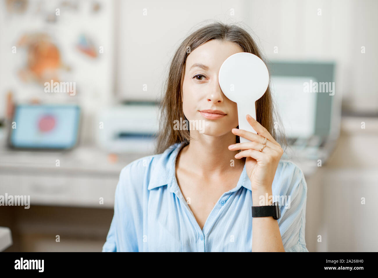 Young woman checking vision covering one eye with an ophthalmic scapula ...