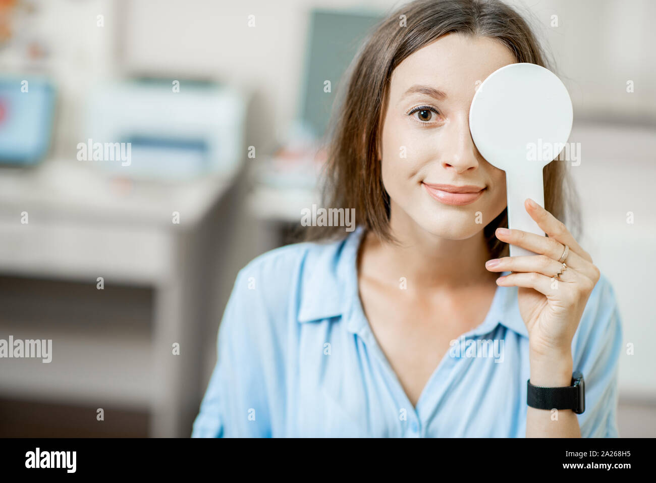 Young woman checking vision covering one eye with an ophthalmic scapula ...