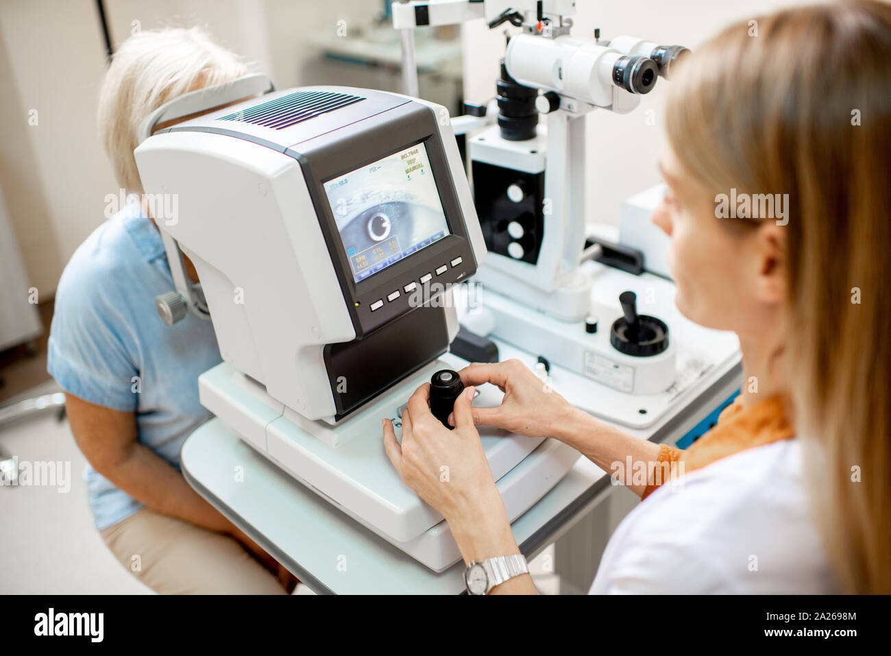 Ophthalmologist examining eyes of a senior patient using digital ...