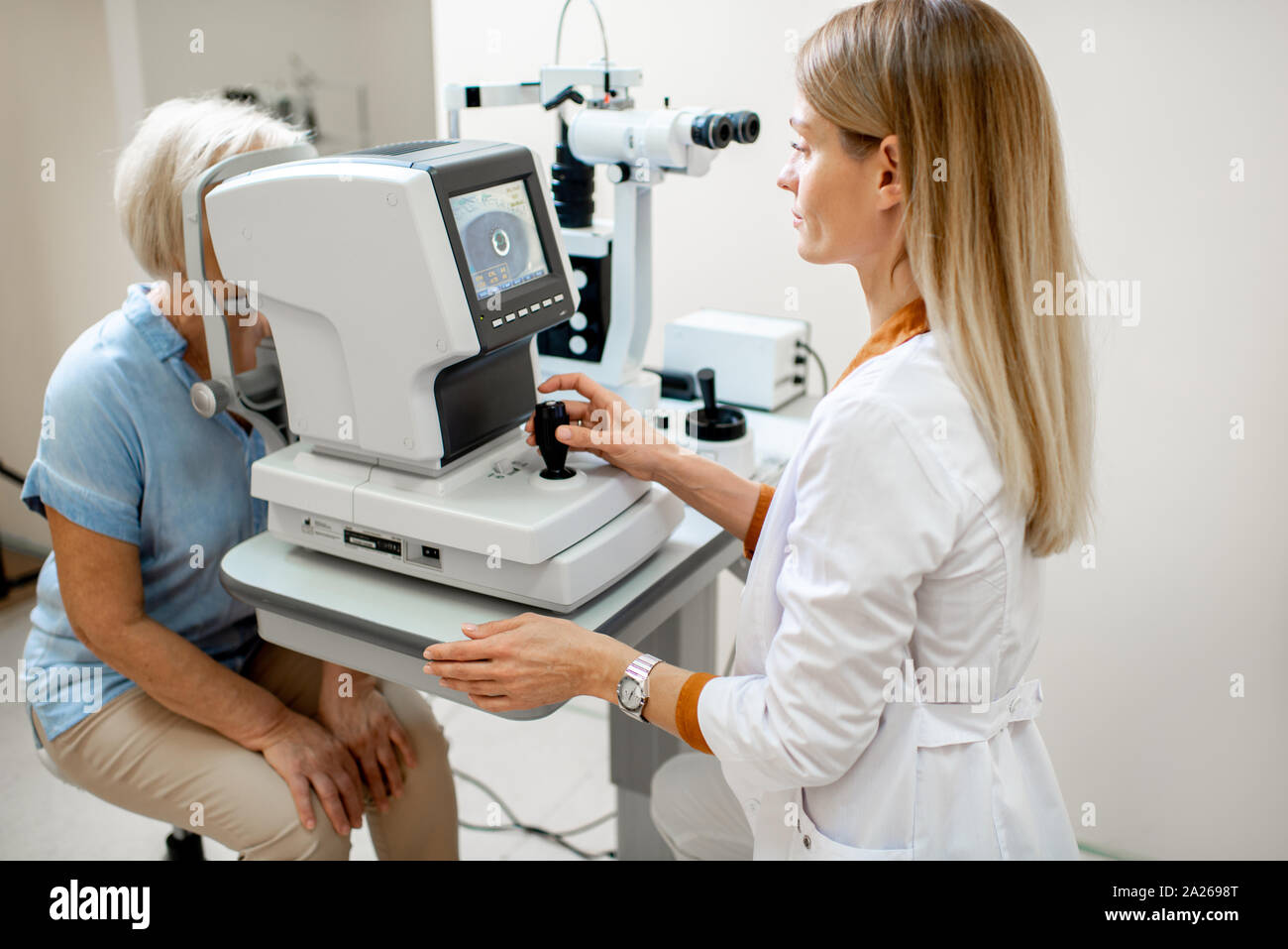 Ophthalmologist examining eyes of a senior patient using digital ...