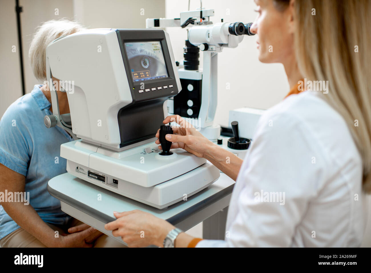 Ophthalmologist examining eyes of a senior patient using digital ...
