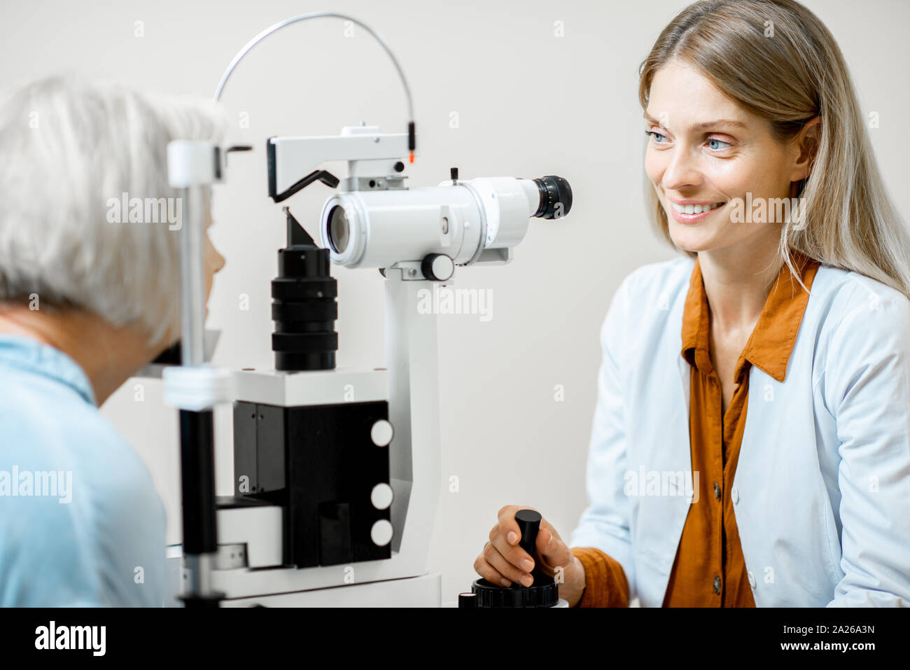 Cheerful ophthalmologist examining eyes of a senior patient using ...