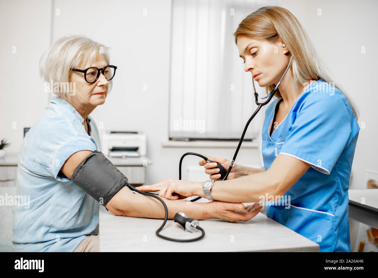 Nurse measuring blood pressure of a senior woman patient with tonometr ...