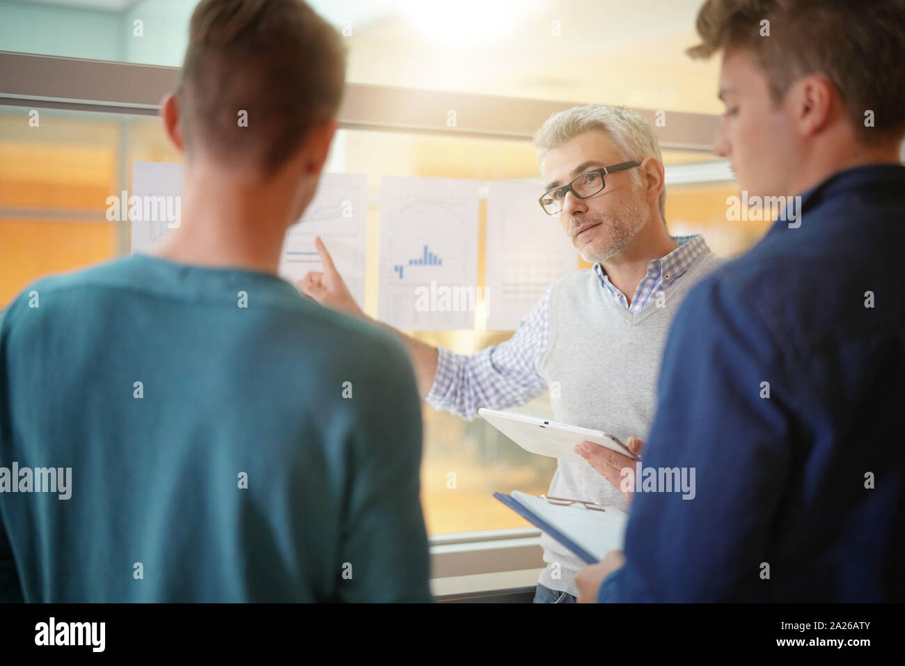 Teacher in classroom teaching economics to young people Stock Photo - Alamy