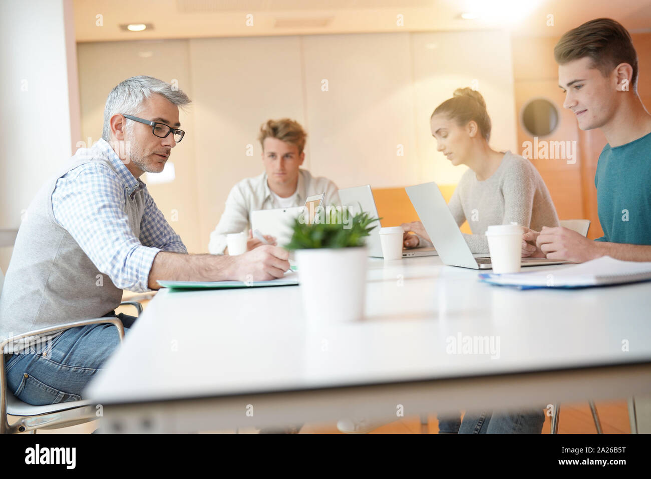 Teacher meeting around table with students Stock Photo - Alamy
