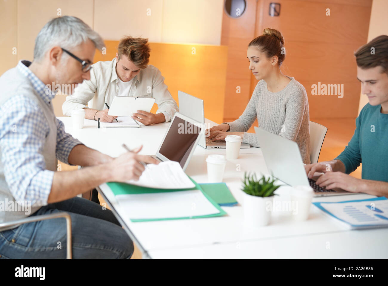 Teacher meeting around table with students Stock Photo - Alamy