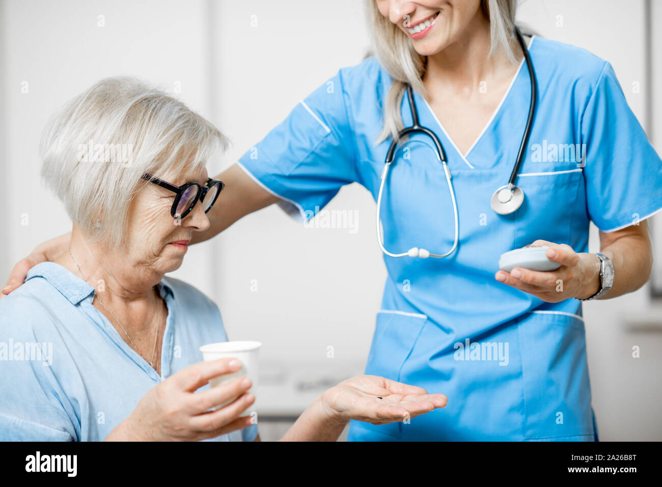 Nurse giving some medicine for a senior woman sitting on the couch ...