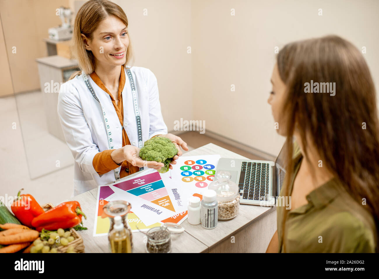 Nutritionist with young woman client talking about meal plan and ...