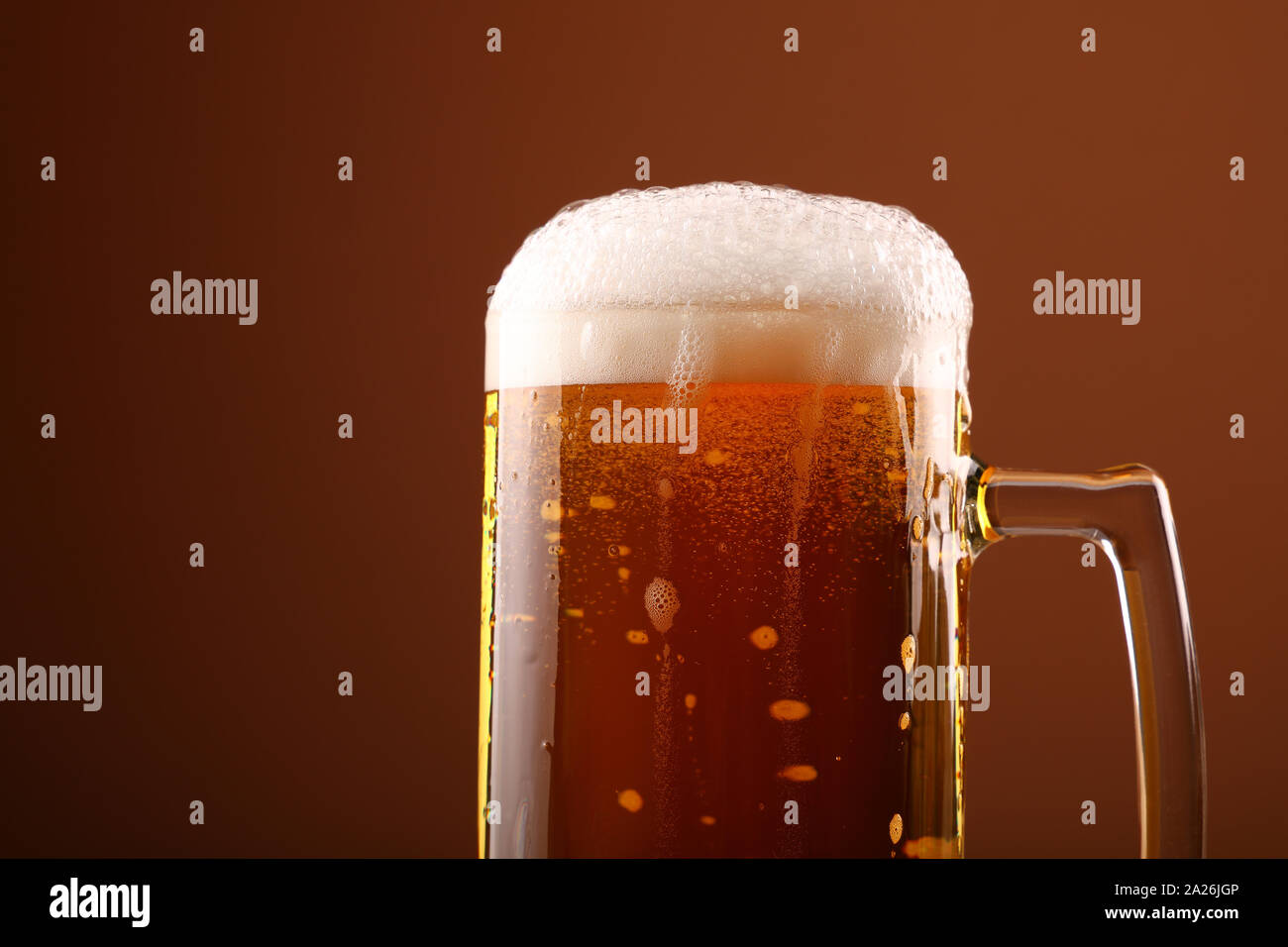 Close up pouring lager beer with white froth and bubbles in glass mug ...