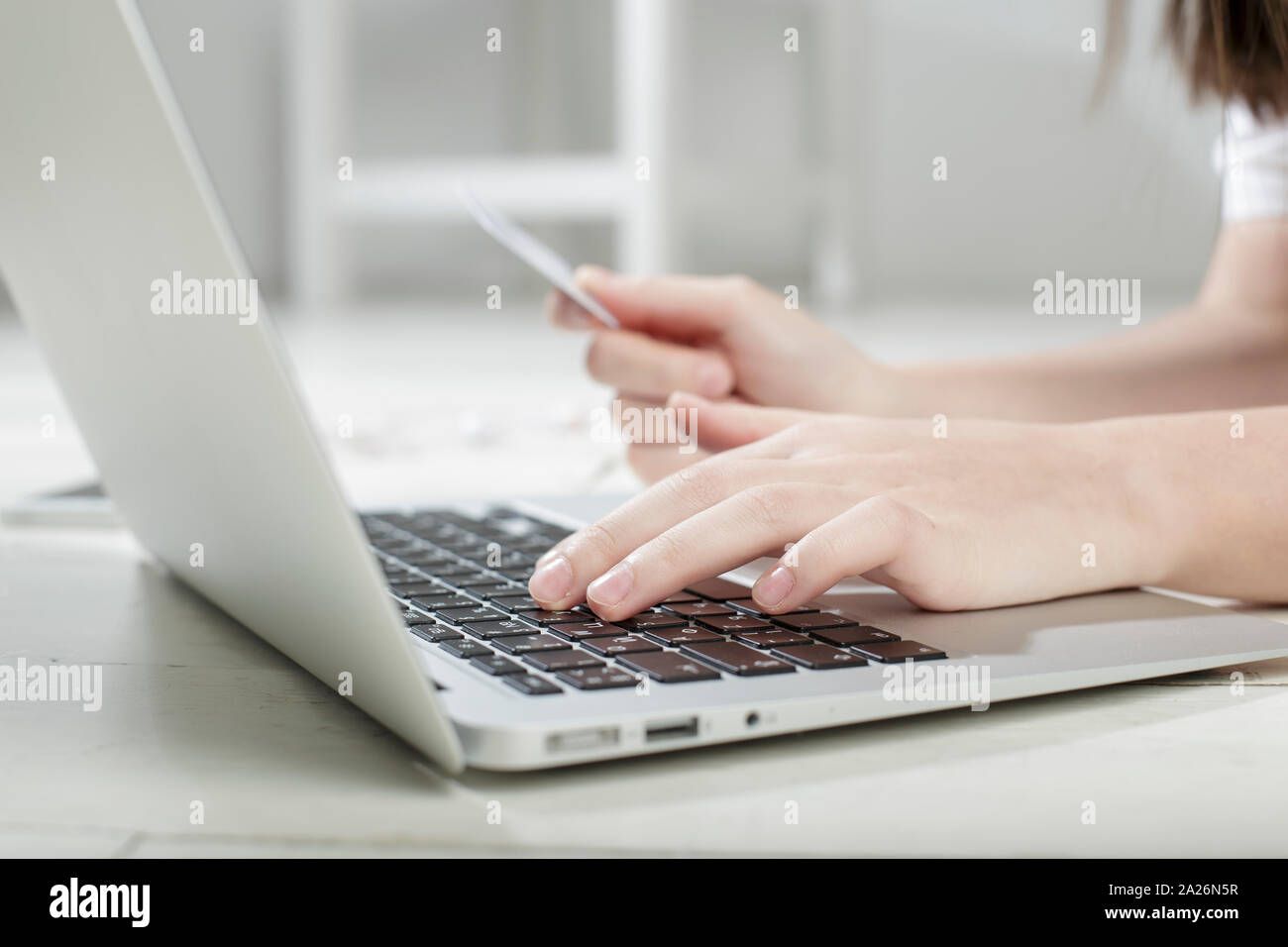 Girl with a credit card in light colored clothes typing using hands on ...