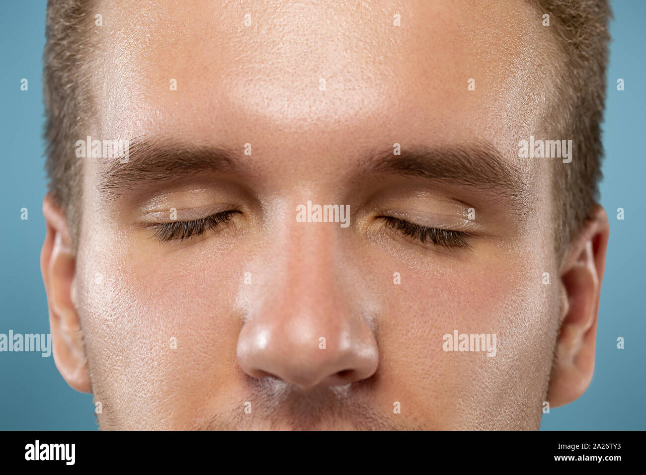 Caucasian young man's close up portrait on blue studio background ...