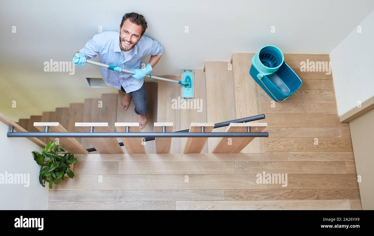 Housekeeper with mop while cleaning stairs and parquet floor Stock ...