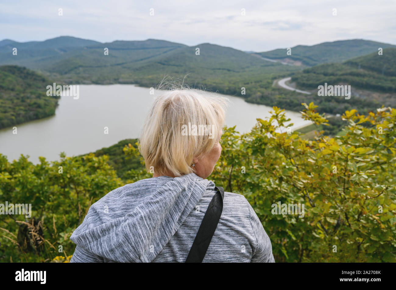 Aged woman looking in distance on top of the hill. View from back Stock ...