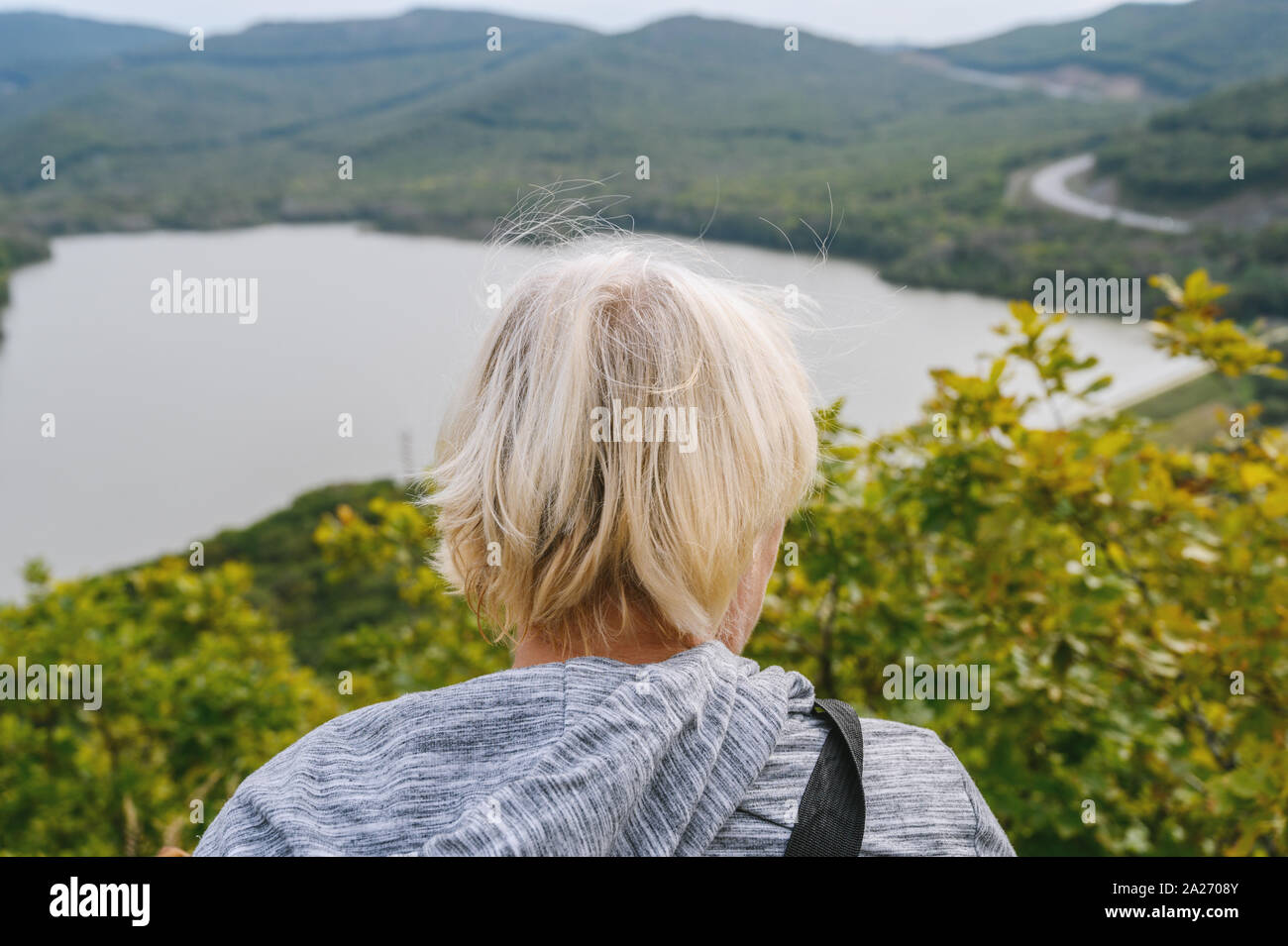 Aged woman looking in distance on top of the hill. View from back Stock ...