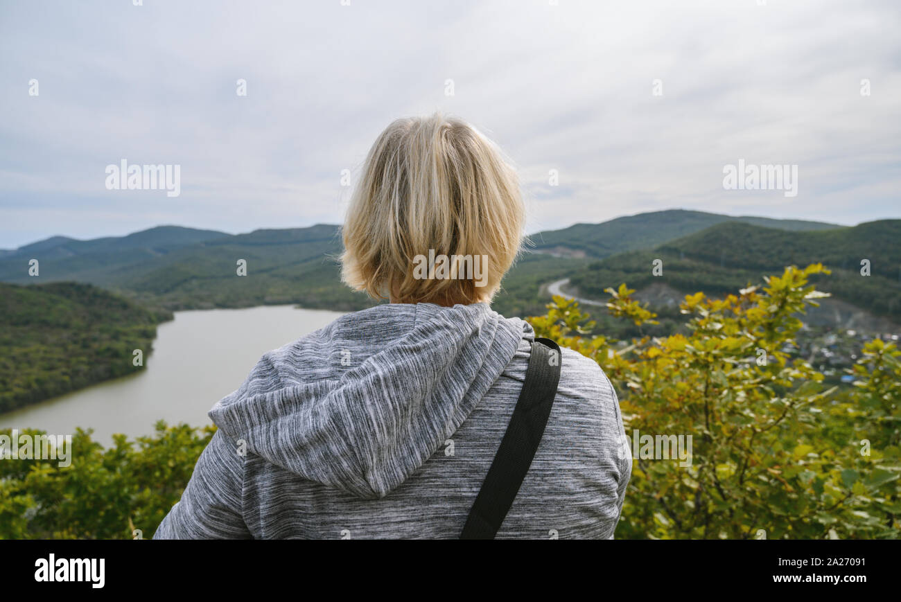 Aged woman looking in distance on top of the hill. View from back Stock ...