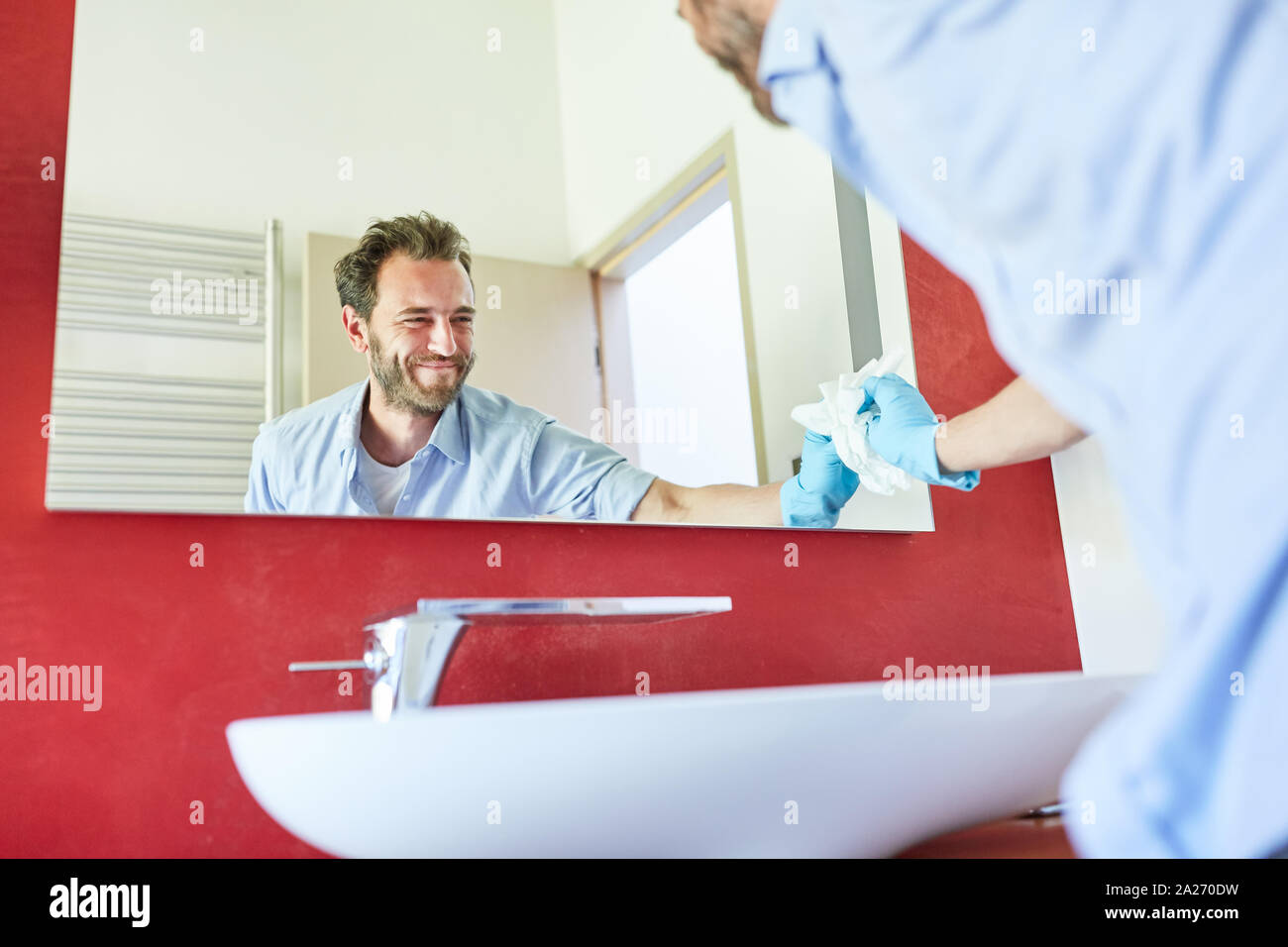 Cleaning man as a houseman with cleaning cloth in the bathroom at the ...