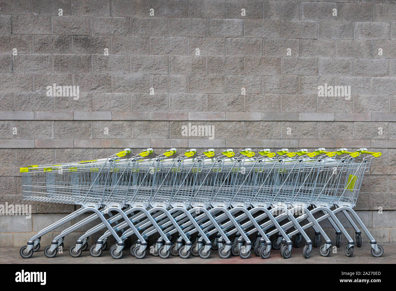 Many shopping trolleys with yellow handle standing in a row in the ...